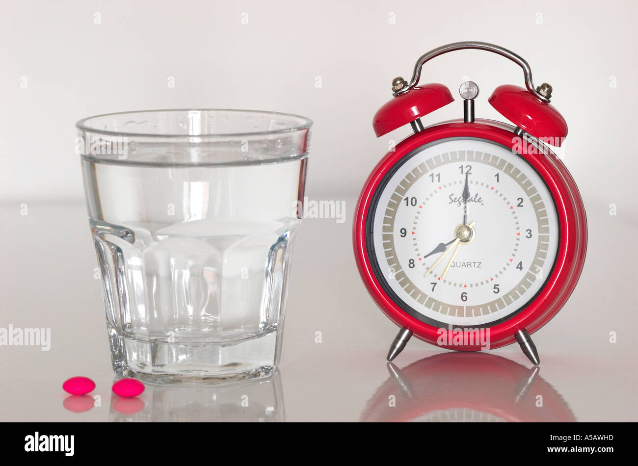 Tablets glass of water and alarm clock Stock Photo - Alamy