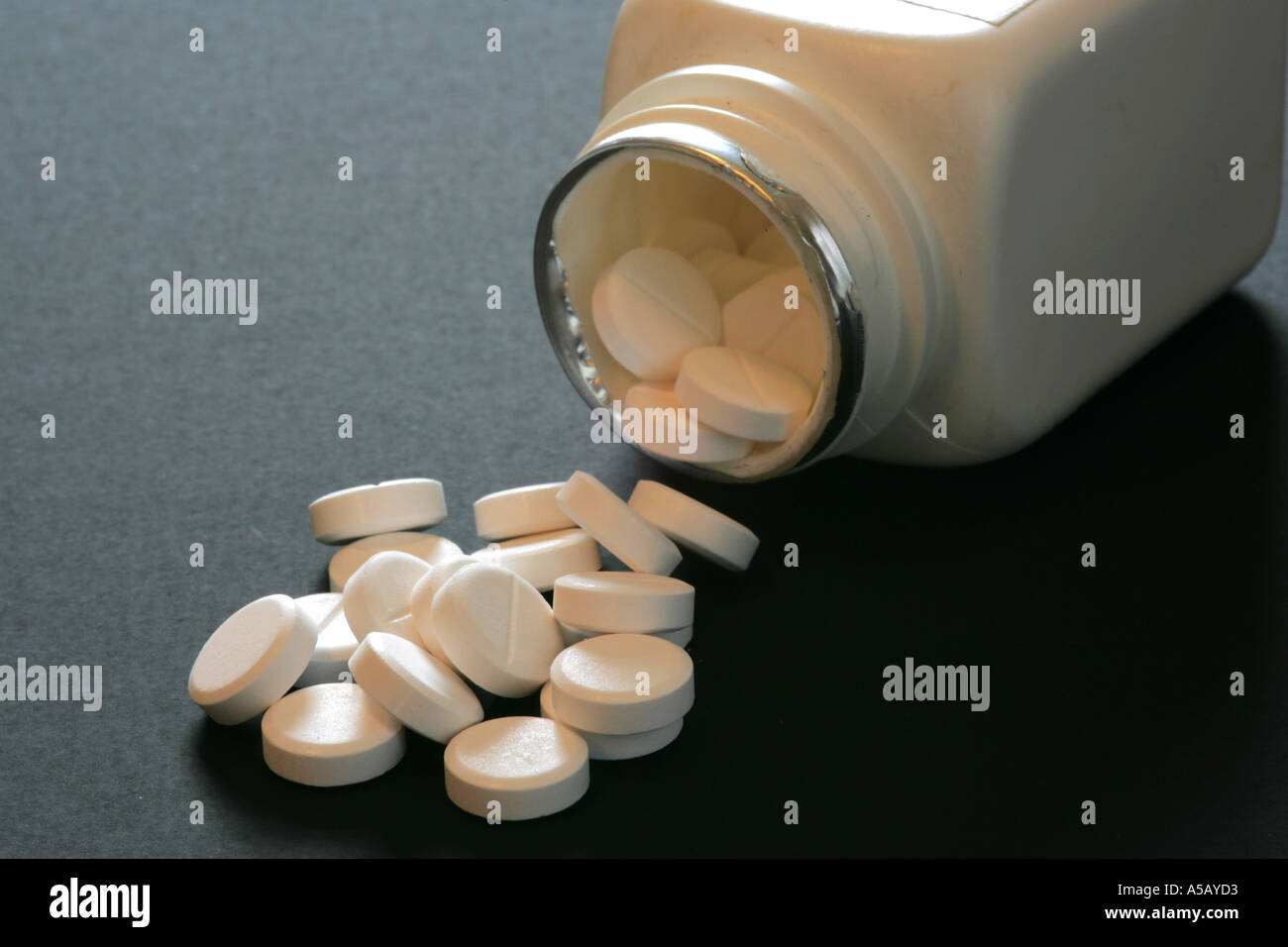 White pills capsule tablets falling out of a generic white medicine ...