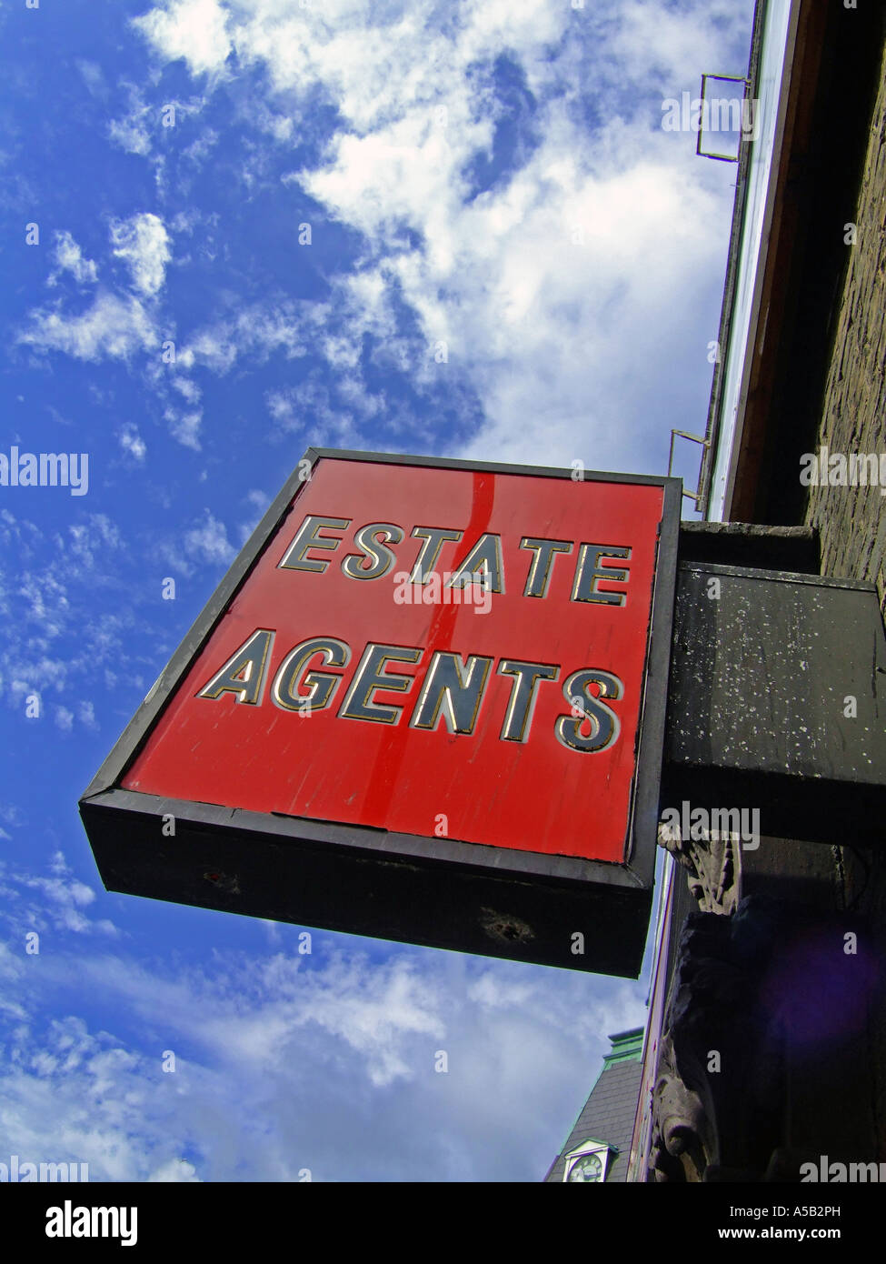 Bright Red Estate Agents sign against blue sky. with copy space on all ...