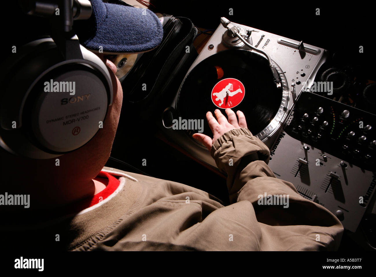 DJ WEARING HEADPHONES USING TWO TURNTABLES AND A MIXER Stock Photo - Alamy