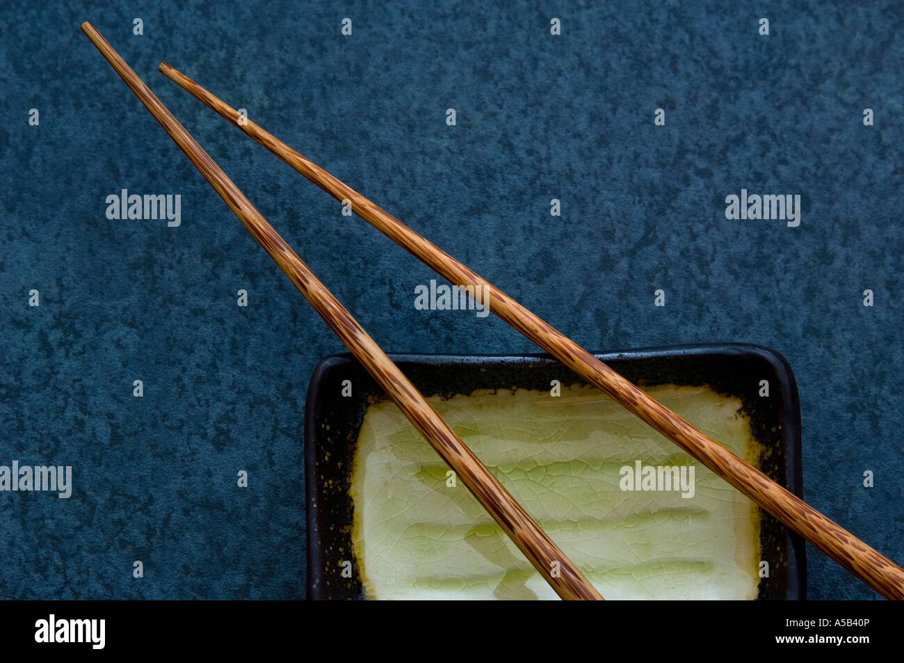 Wooden chopsticks with dish on blue background Stock Photo - Alamy