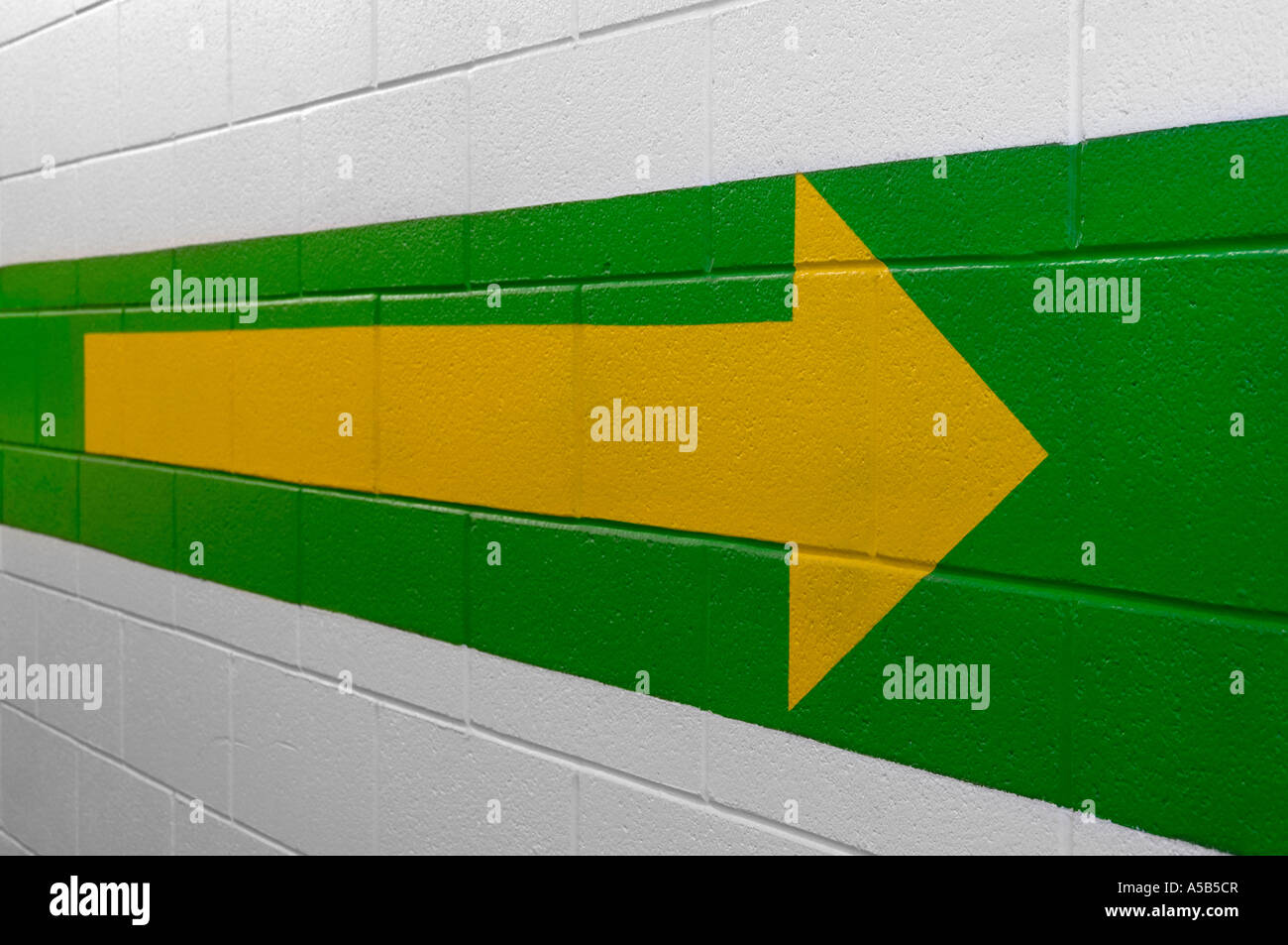 Yellow direction arrow pointing right on cement wall Stock Photo - Alamy