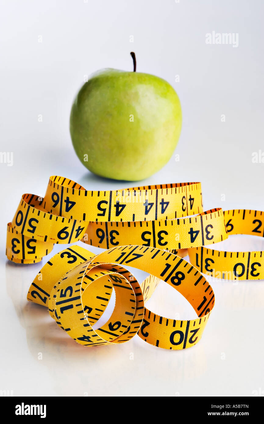 Apple and a tape measure on a reflective tabletop Stock Photo - Alamy