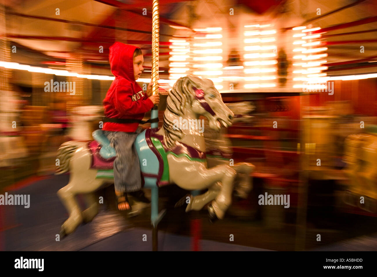 Young boy riding a merry go round at a fair Stock Photo - Alamy