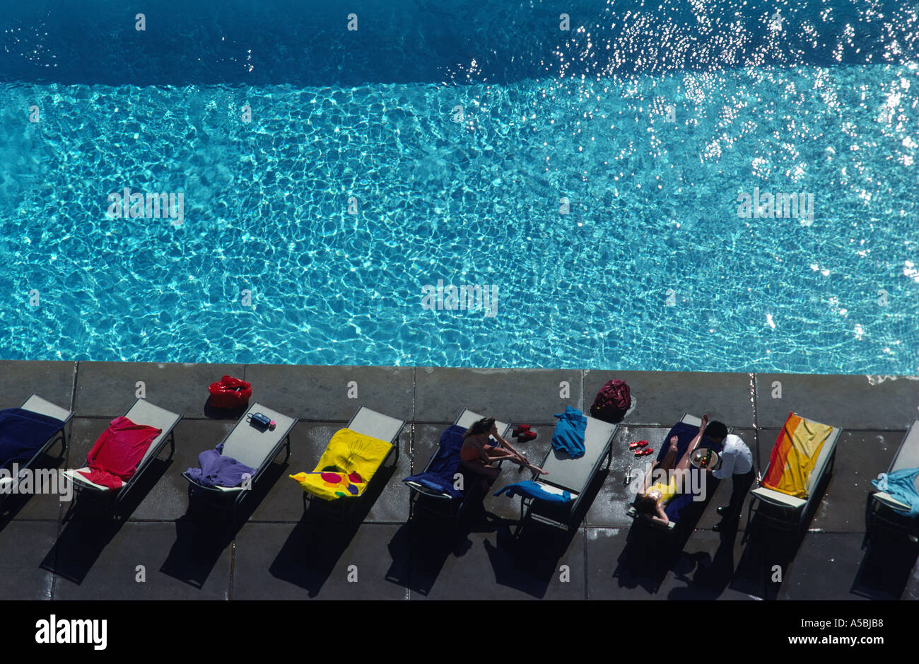 A waiter delivers drinks by the hotel pool to two women on holiday ...