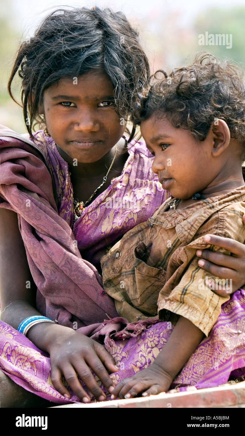 Young lower caste Indian girl sitting cross legged with her baby sister ...