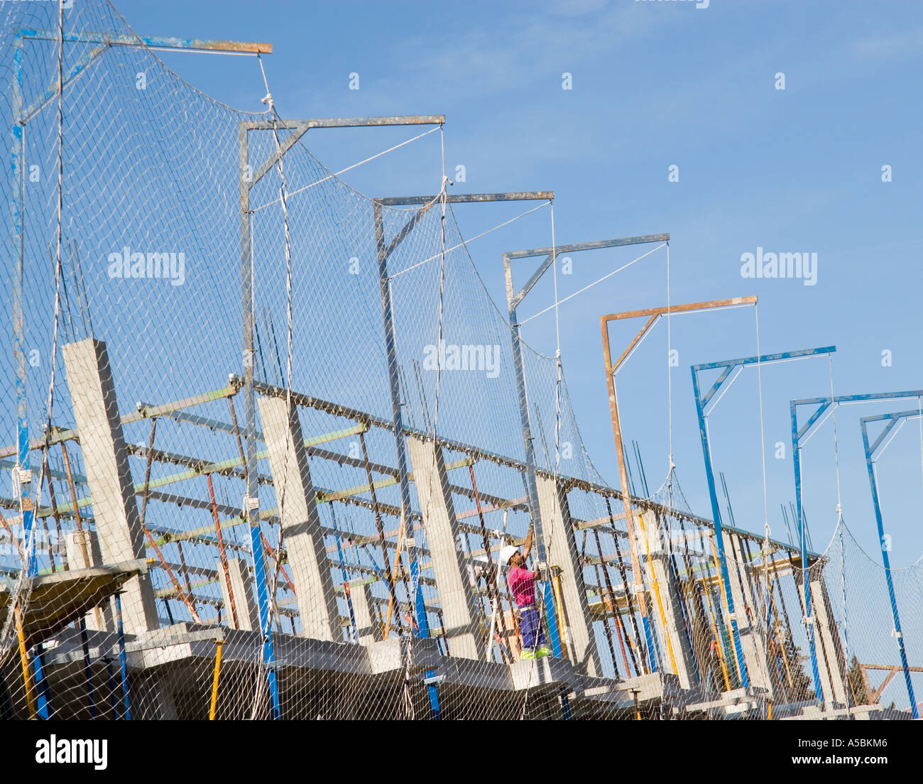 Worker behind safety nets on building under construction Stock Photo ...