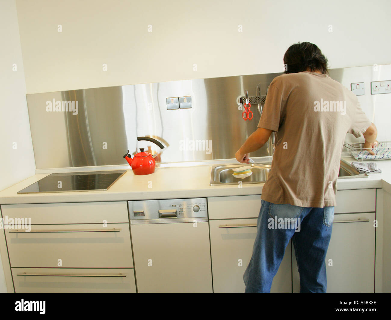Rear view of a young man standing in the kitchen Stock Photo - Alamy