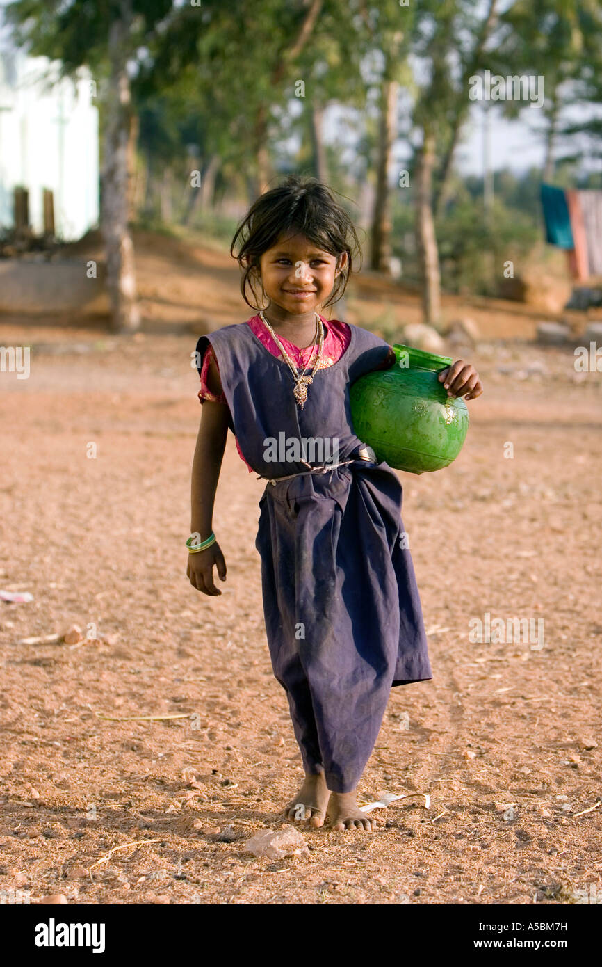 Young poor Indian girl carrying water pot from a village water tap ...