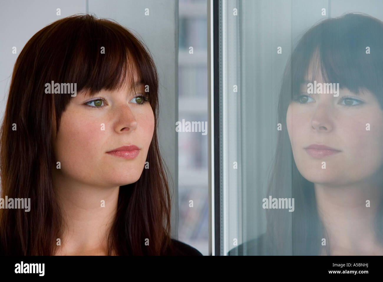 A beautiful young woman stares wistfully into a window where her ...
