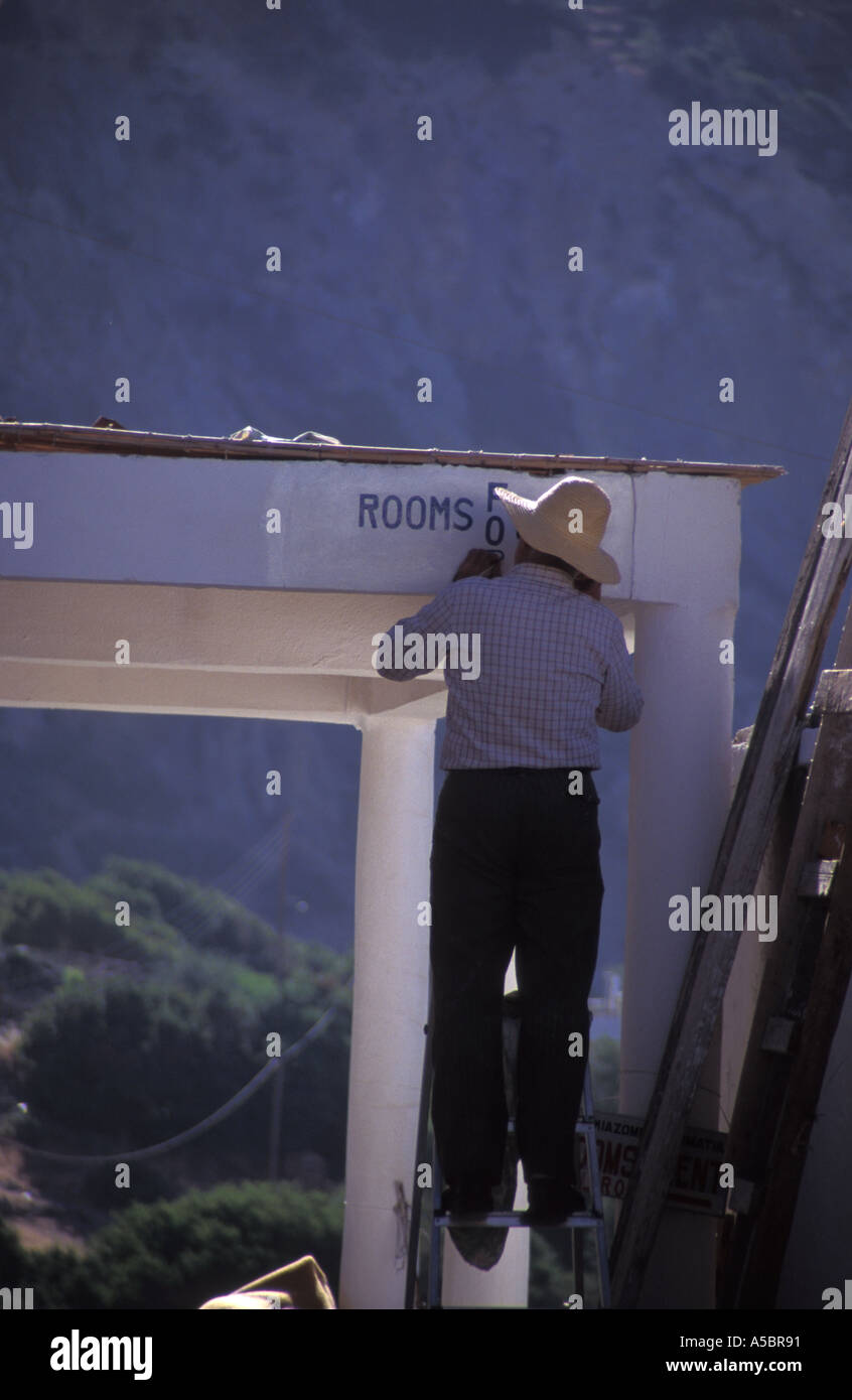 Greece old man painting B&B accommodation sign in mountain village of ...