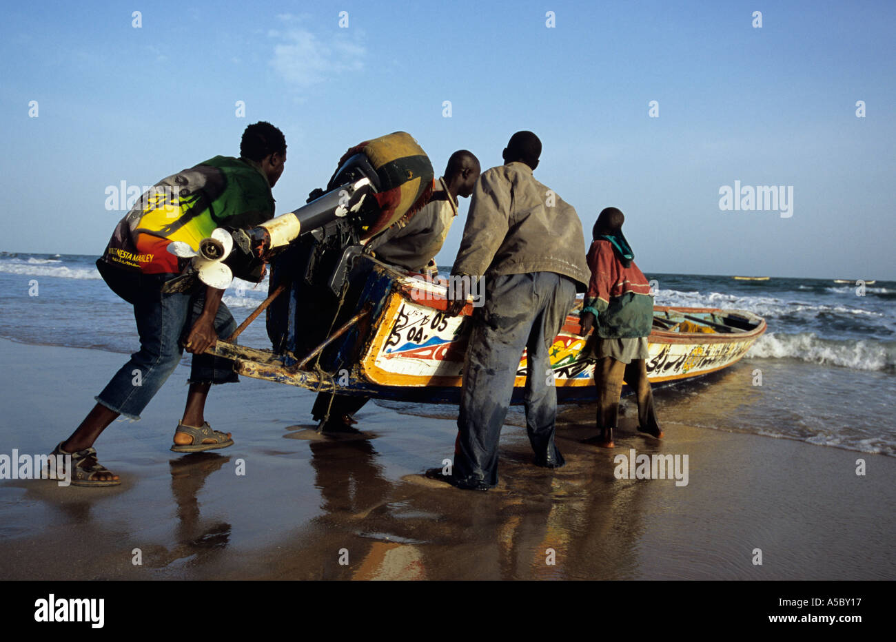 Fishermen in the Gambia West Africa push their boat into the waves ...