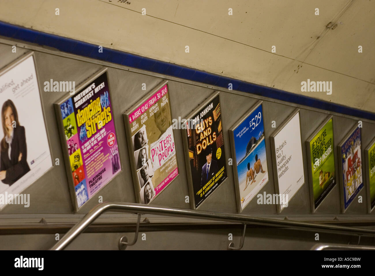 View down an escalator in the London underground with advertising ...