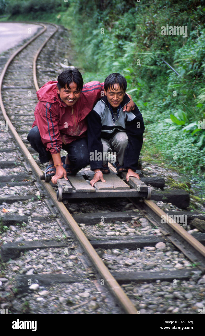 two young men have fun on toy train railway line Darjeeling District ...