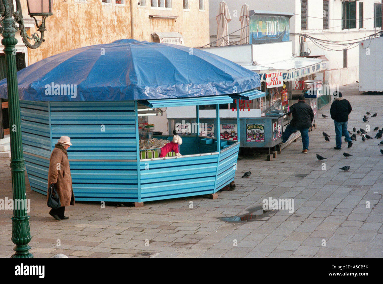 Market stall; old lady dressed in a full length fur coat is watched by ...