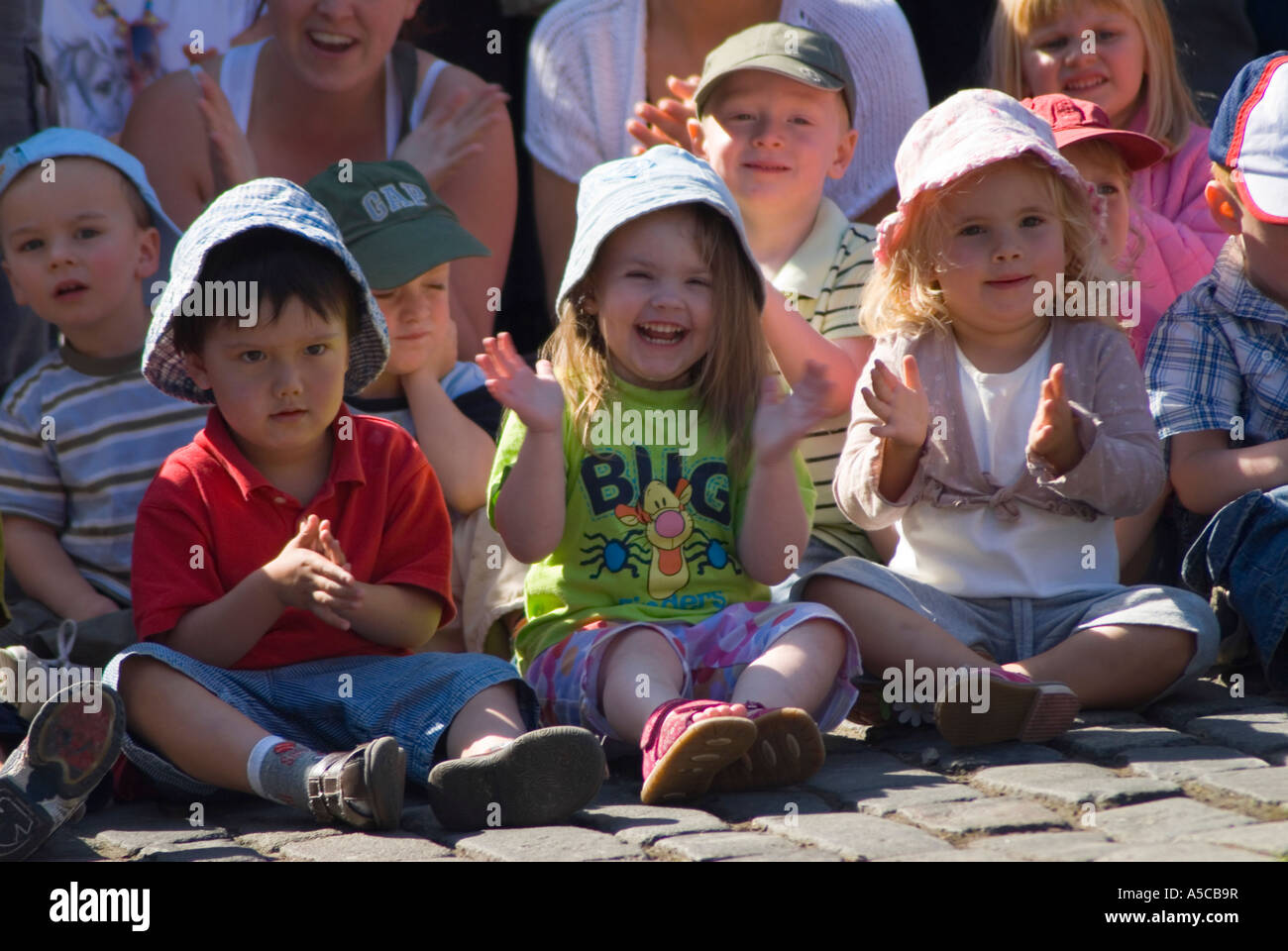 children laughing and clapping while watching a street perfomance show ...