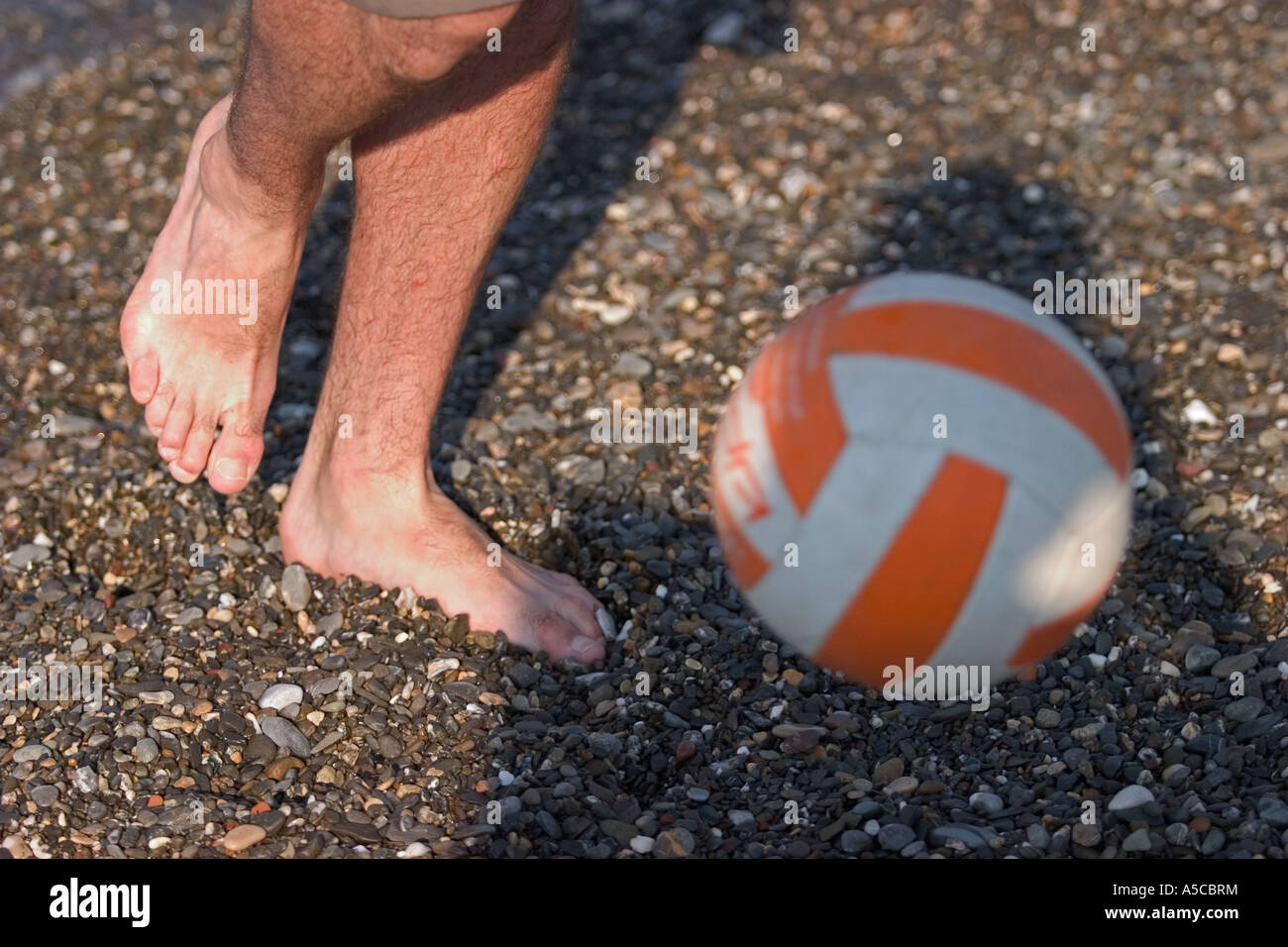 Young boy running to kick ball on a beach Stock Photo - Alamy