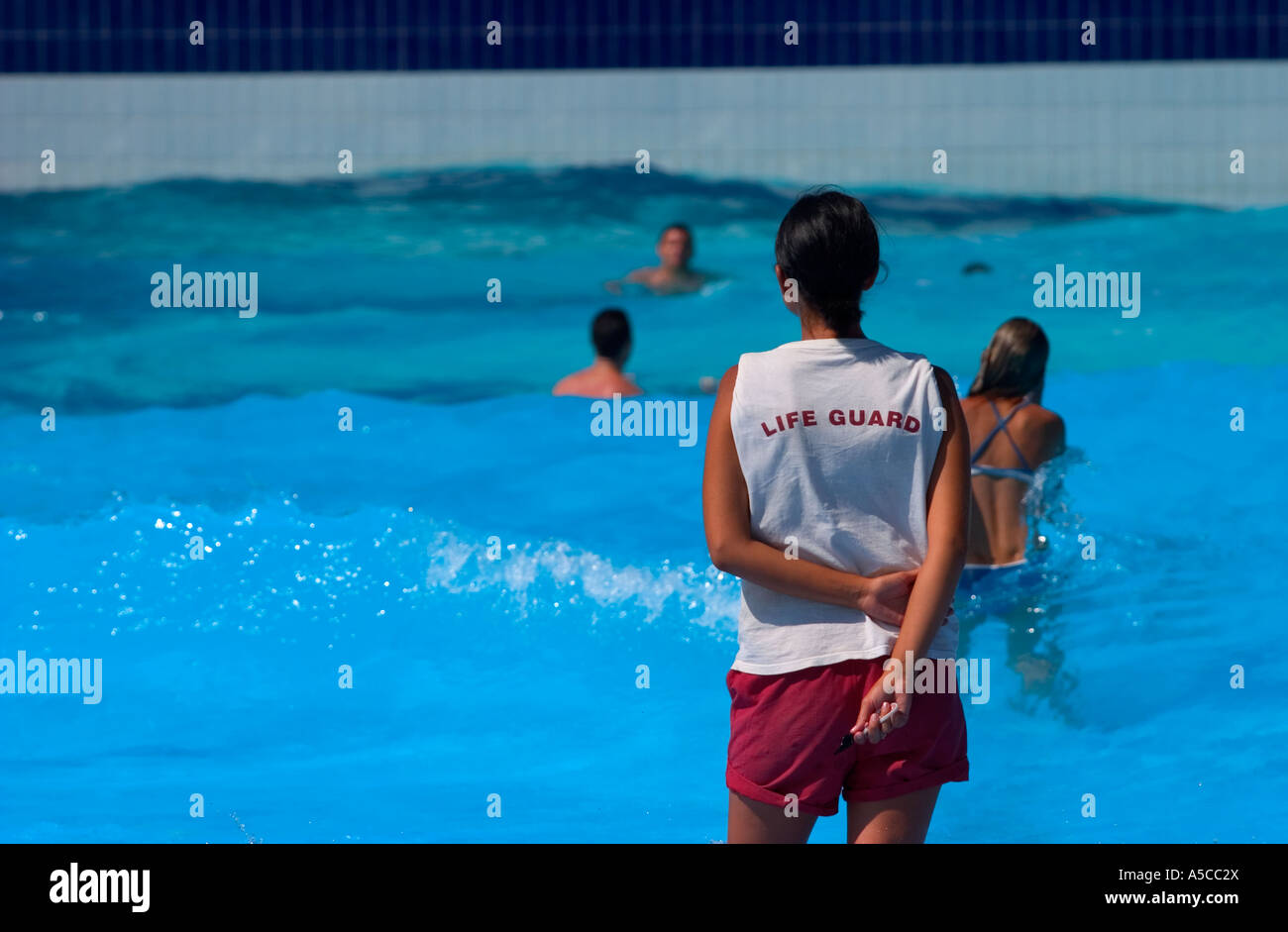 a lifeguard woman standing up watching the pool in water park waterpark ...