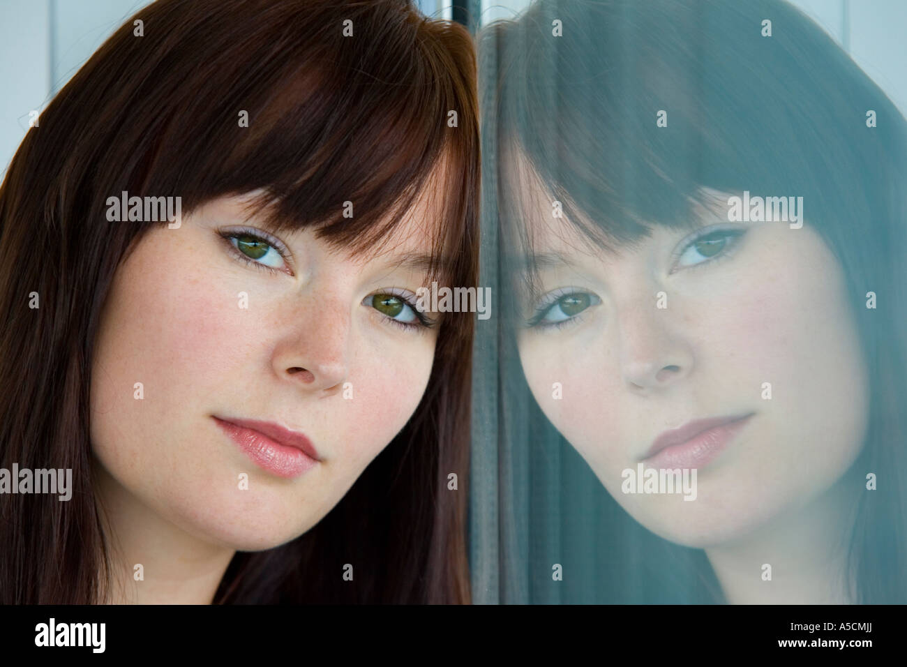 A beautiful young woman stares wistfully into a window where her ...