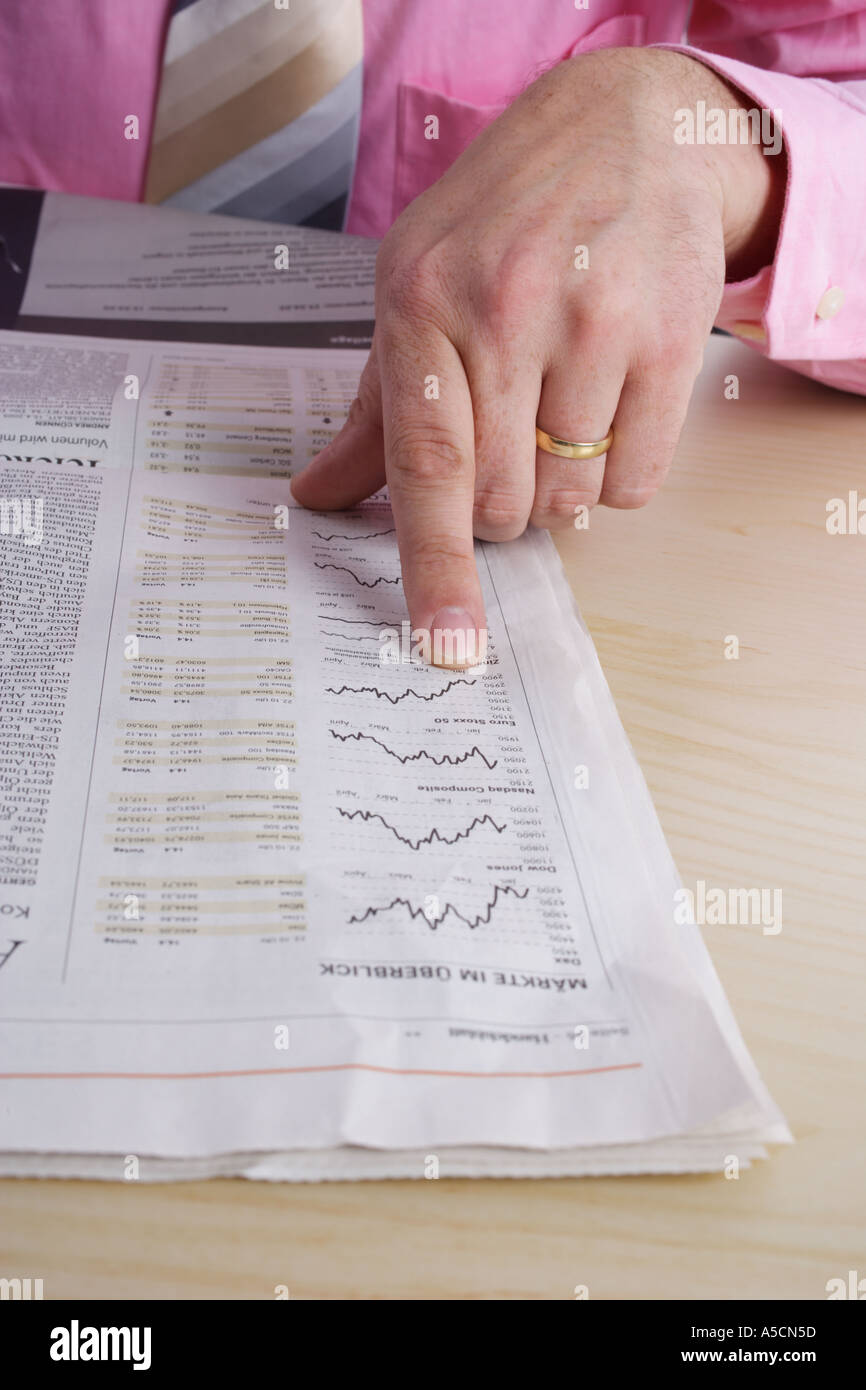 Businessman reading a newspaper pointing at stock charts Stock Photo ...