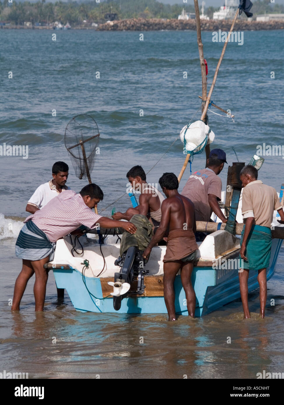 Fishermen push their boat to sea in the port Stock Photo - Alamy