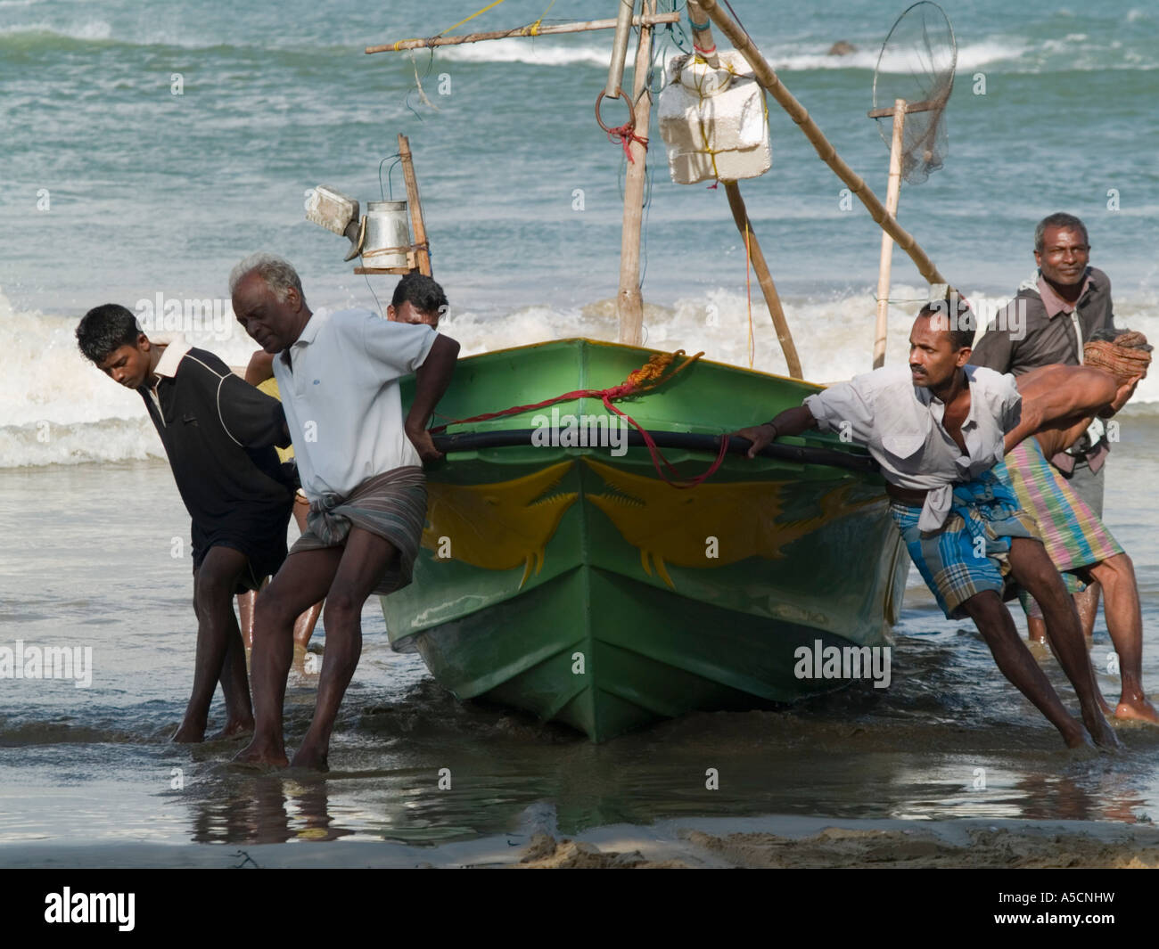 Fishermen push their boat to sea in the port Stock Photo - Alamy