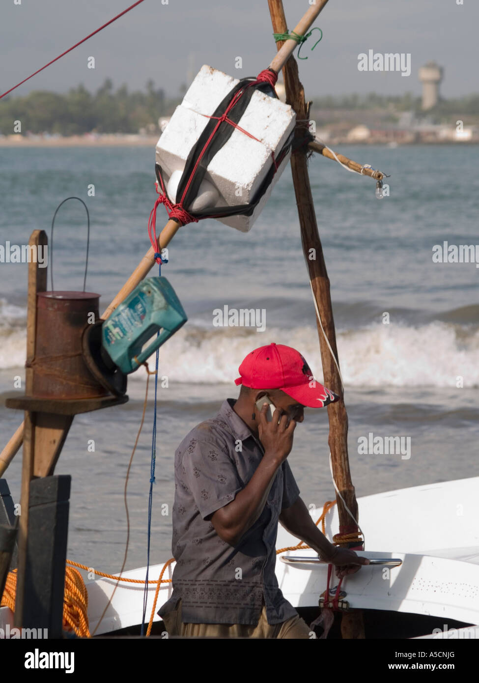 Fisherman uses phone as he waits by his boat in the port Stock Photo ...