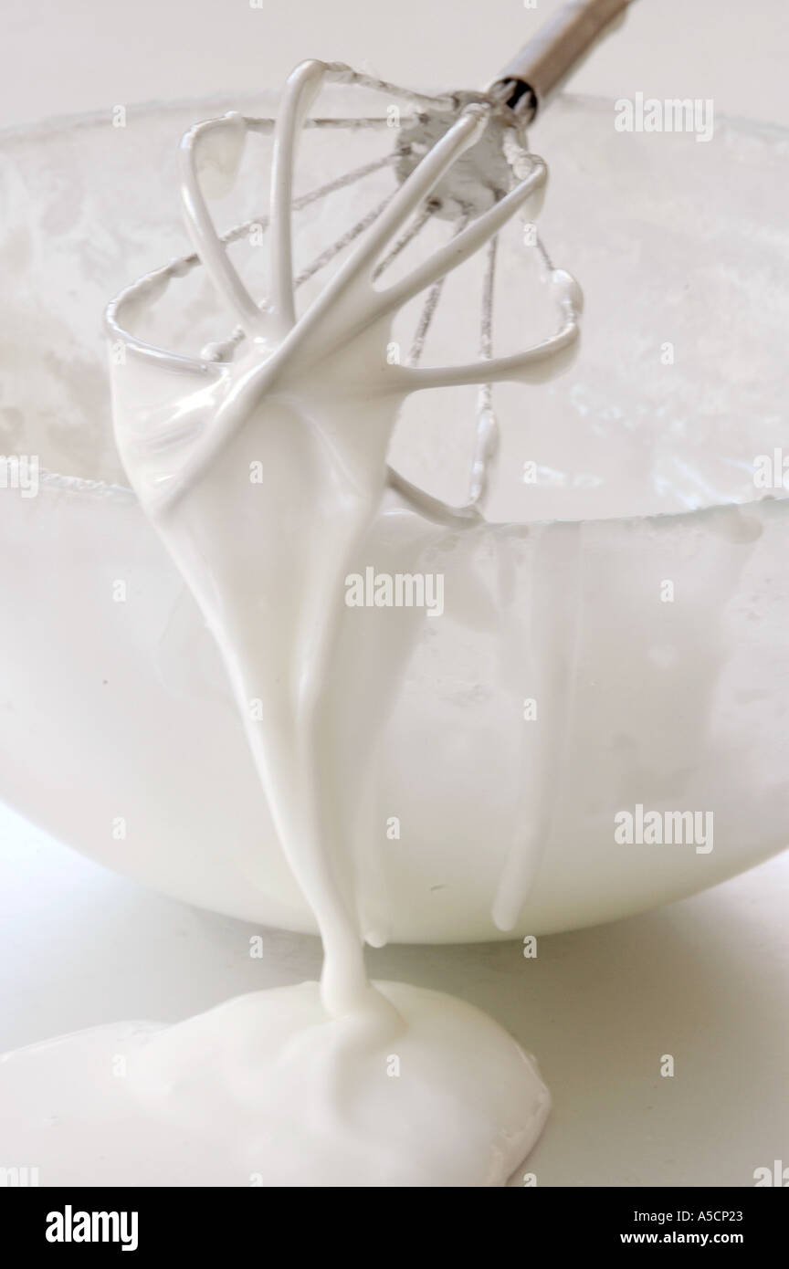 Bowl of white icing with dripping balloon whisk Stock Photo - Alamy
