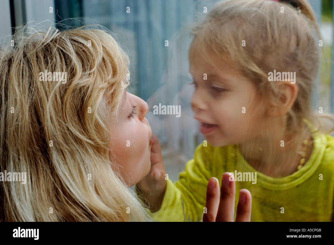 Girl (2-3) and mother face to face through screen door Stock Photo - Alamy