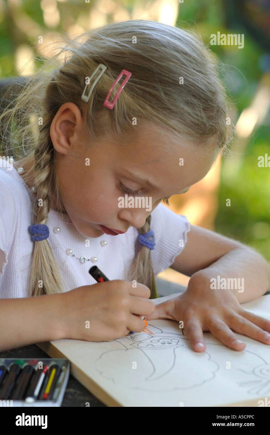 Girl (6-7) drawing with crayons at table Stock Photo - Alamy