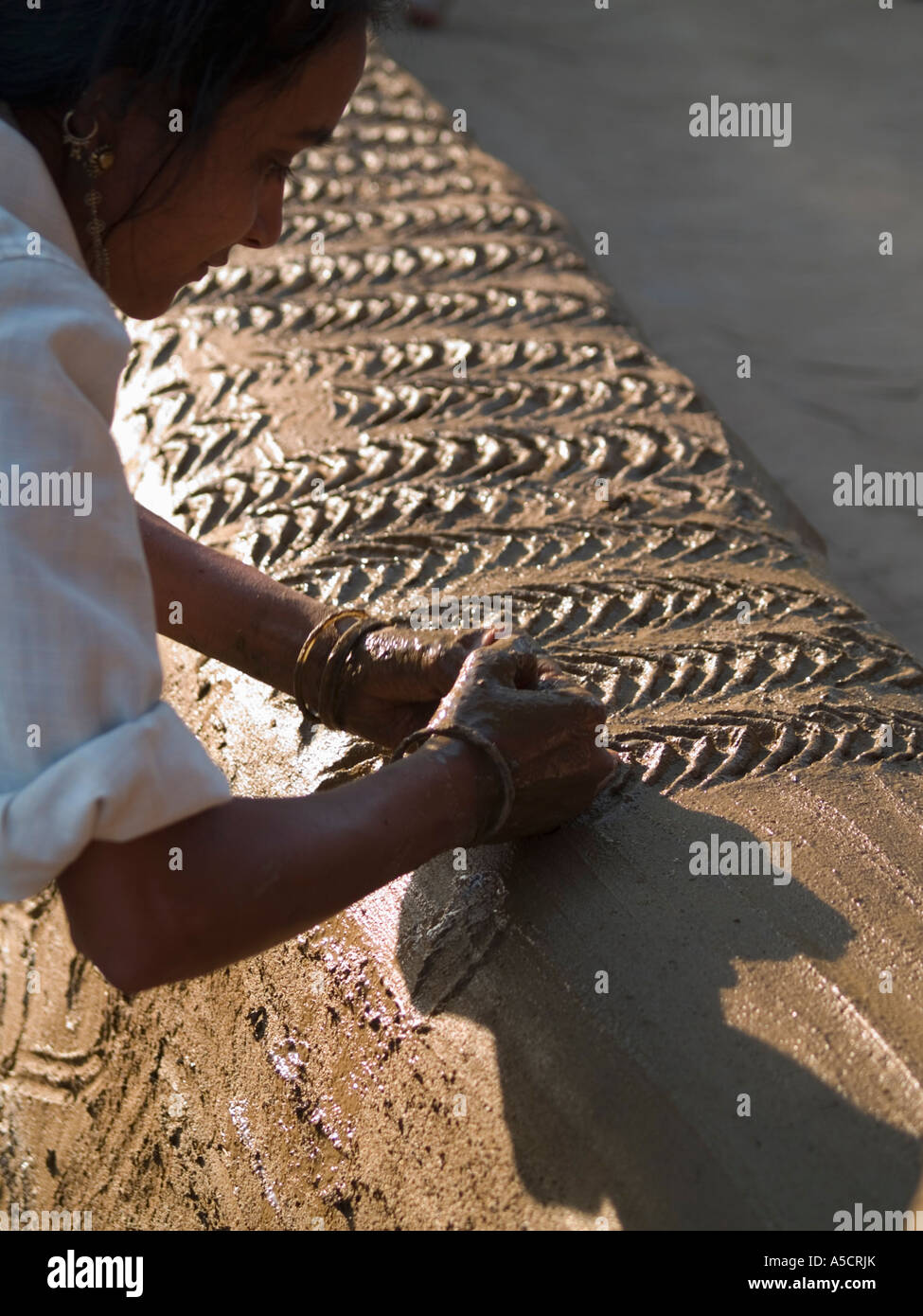 Decorating by hand mud walls made from cow dung Stock Photo - Alamy