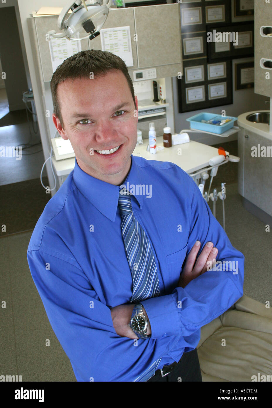 Dentist standing in his dental office with a smile and confident look ...
