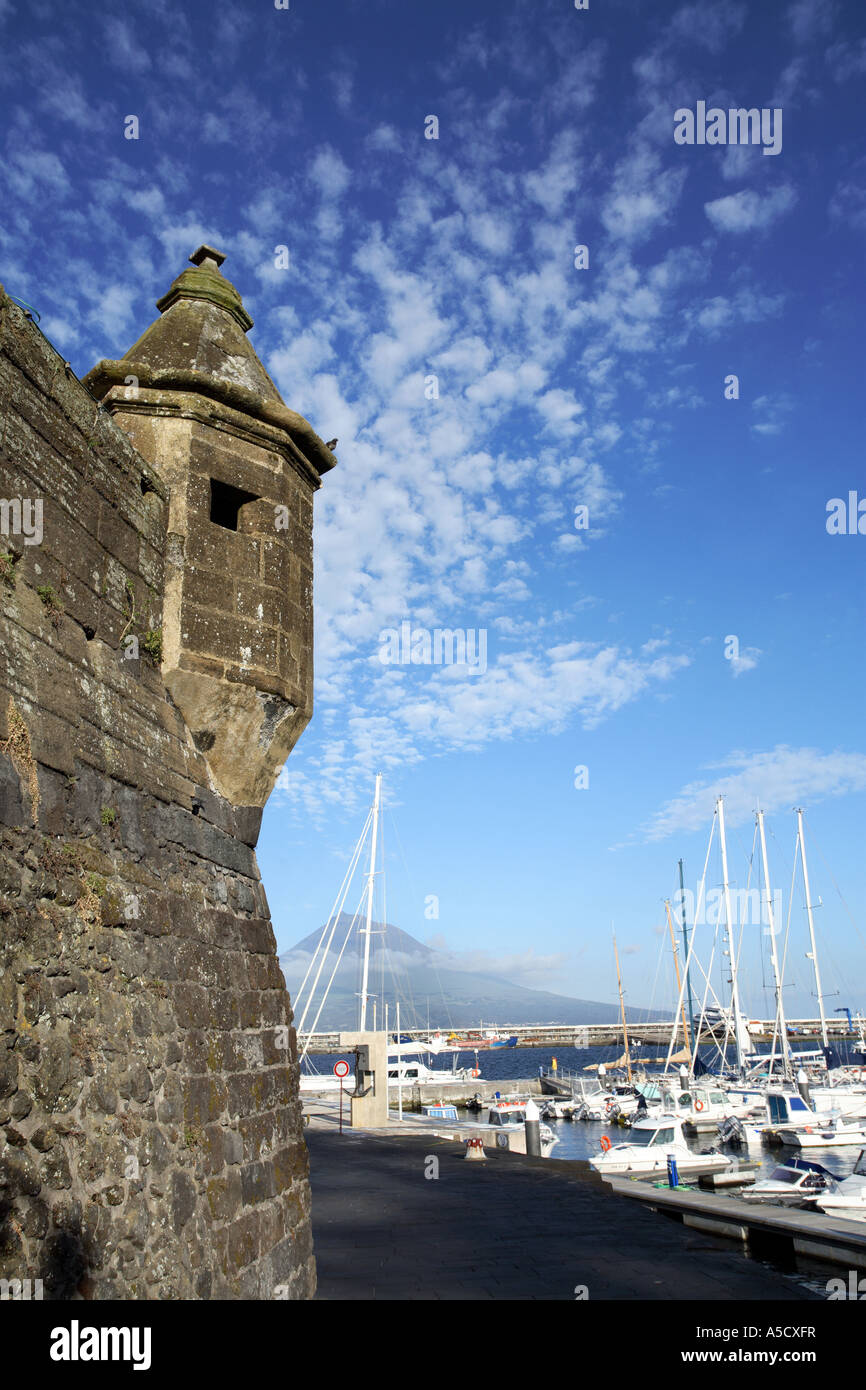 An old fort looming over the modern harbor of Faial, with the island of ...
