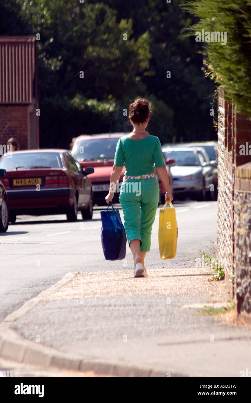 Middle aged woman walking along road with shopping Stock Photo - Alamy