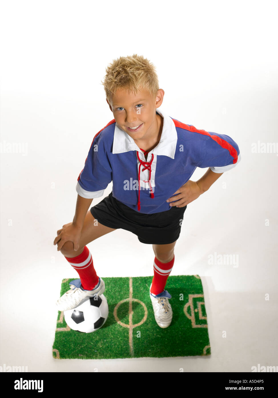 Boy (8-11) with foot on football, hand on hips Stock Photo - Alamy