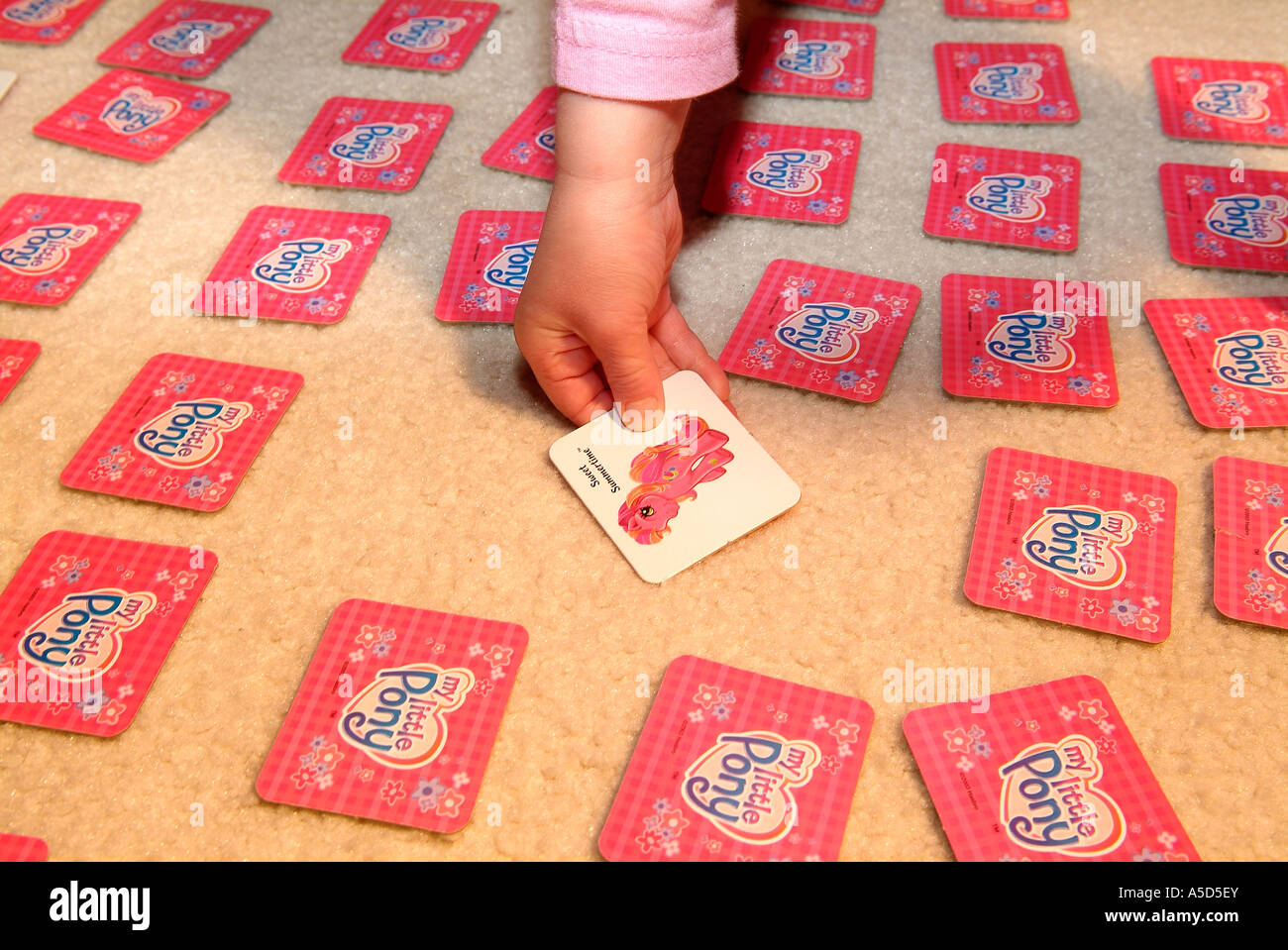 Young girl playing cards on carpet Stock Photo - Alamy