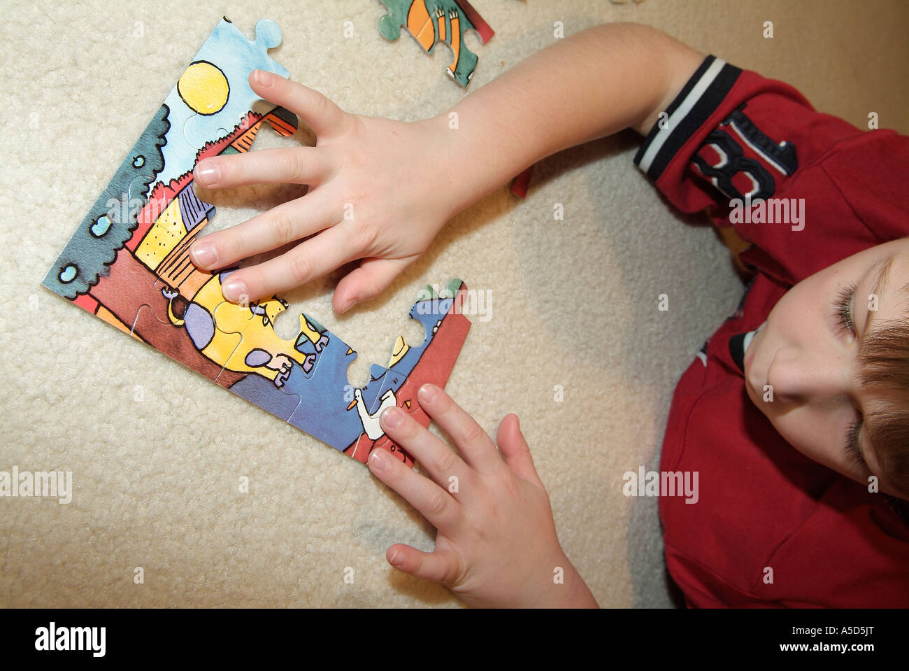Young boy doing jigsaw puzzle on carpet Stock Photo - Alamy