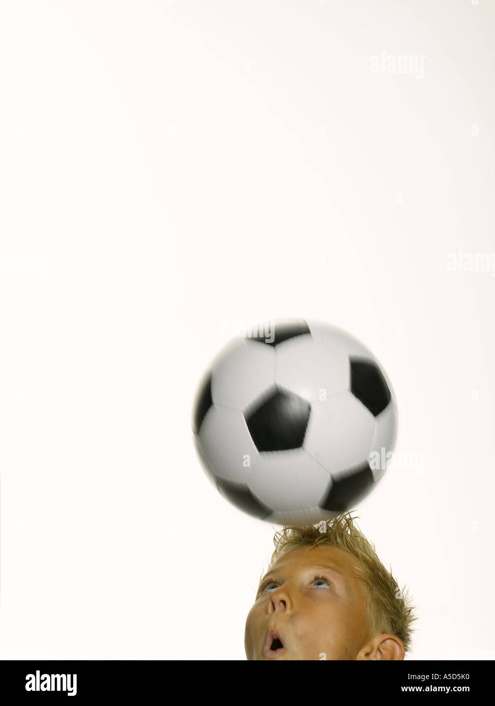 Young boy heading a football Stock Photo - Alamy