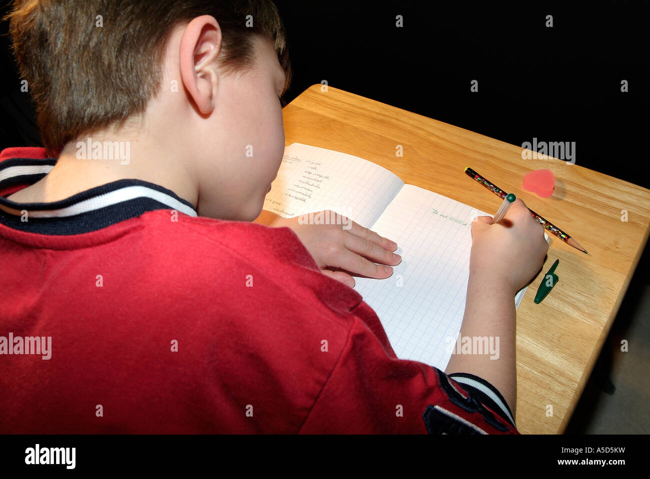 Young boy writing on a notebook with a pen Stock Photo - Alamy