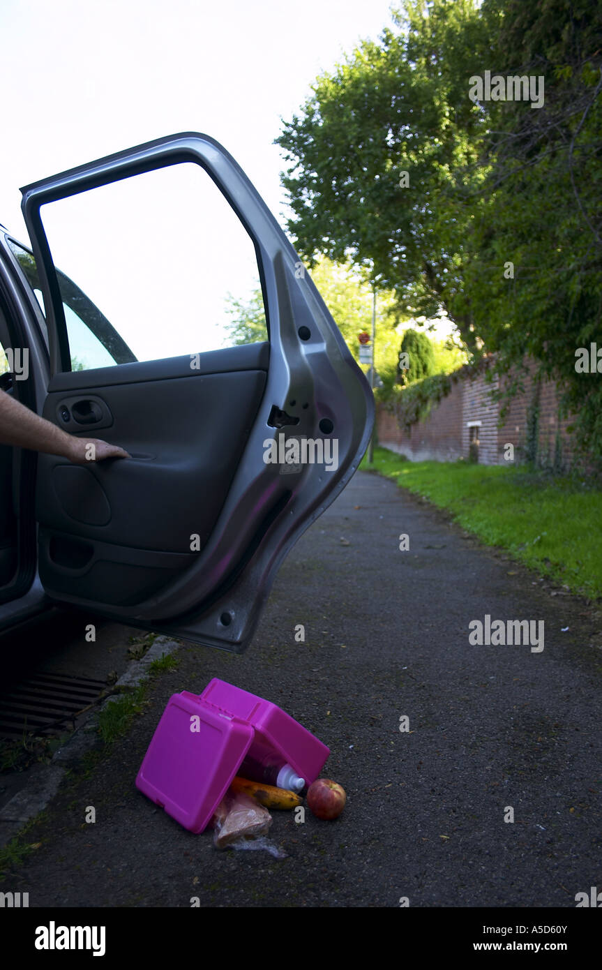 Car pulled up at kerb with dropped or discarded lunch box suggesting ...