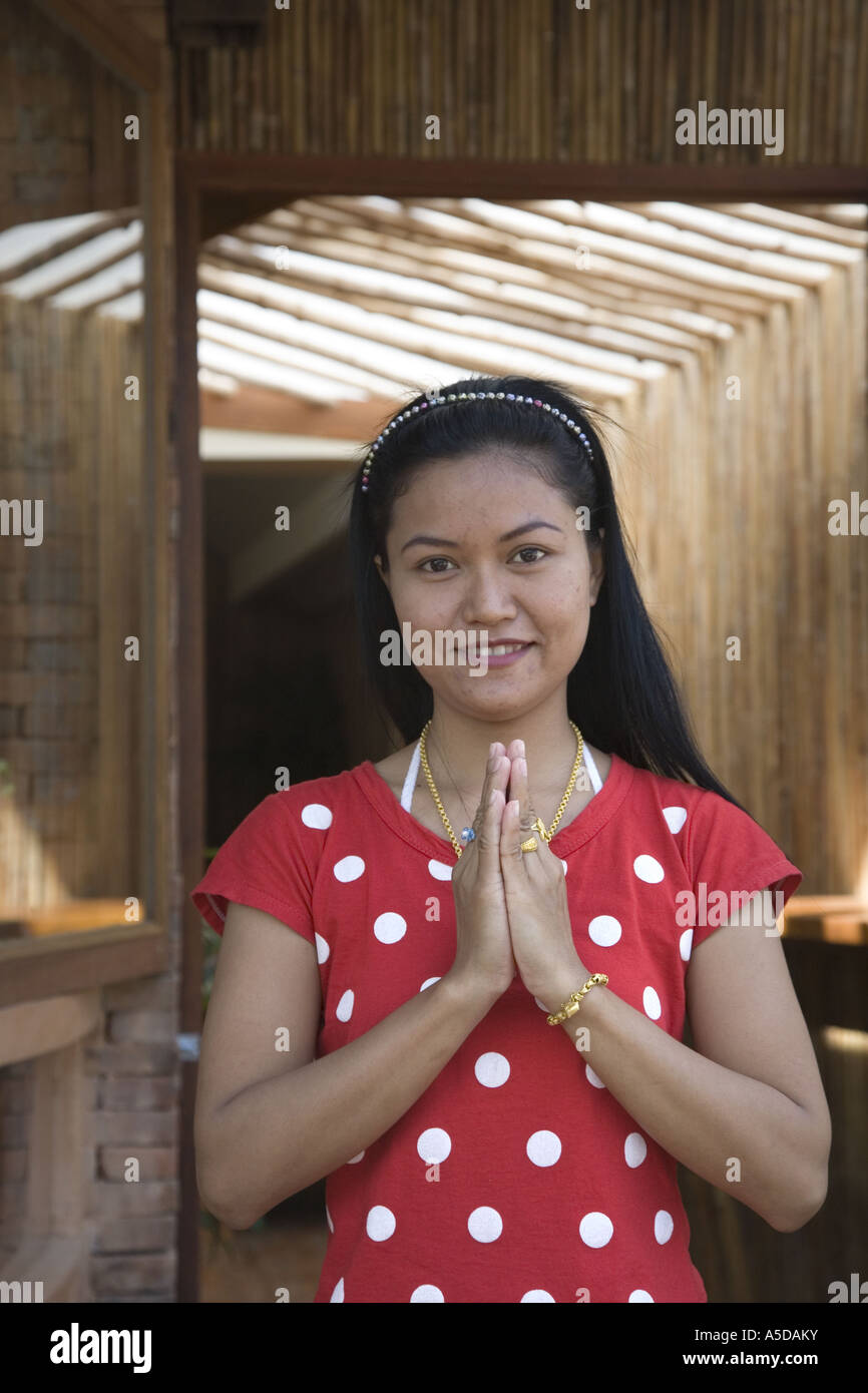 Female thai lady posing in interior with welcoming smile, customary wai ...