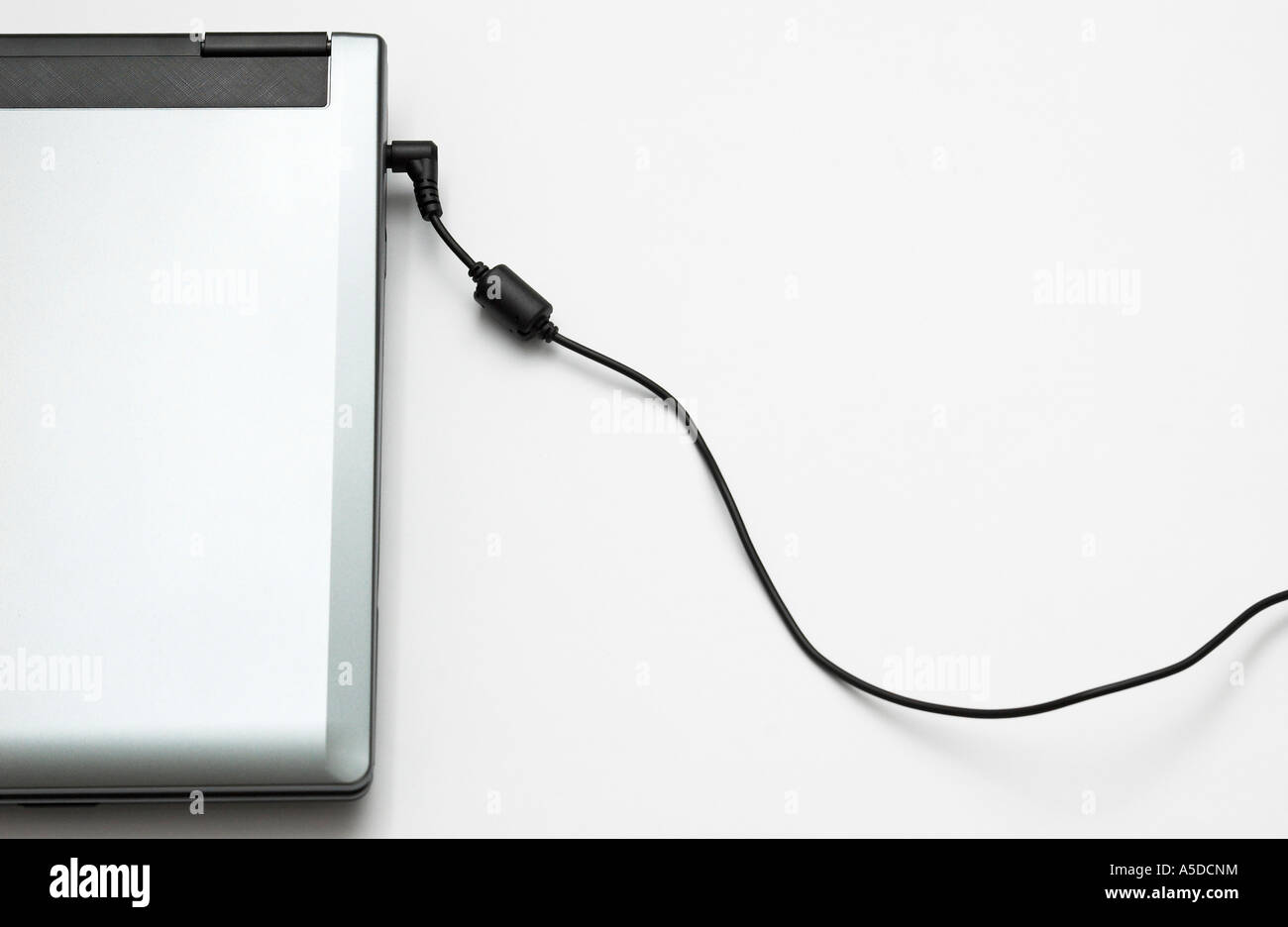 Laptop computer plugged into battery charger Stock Photo - Alamy