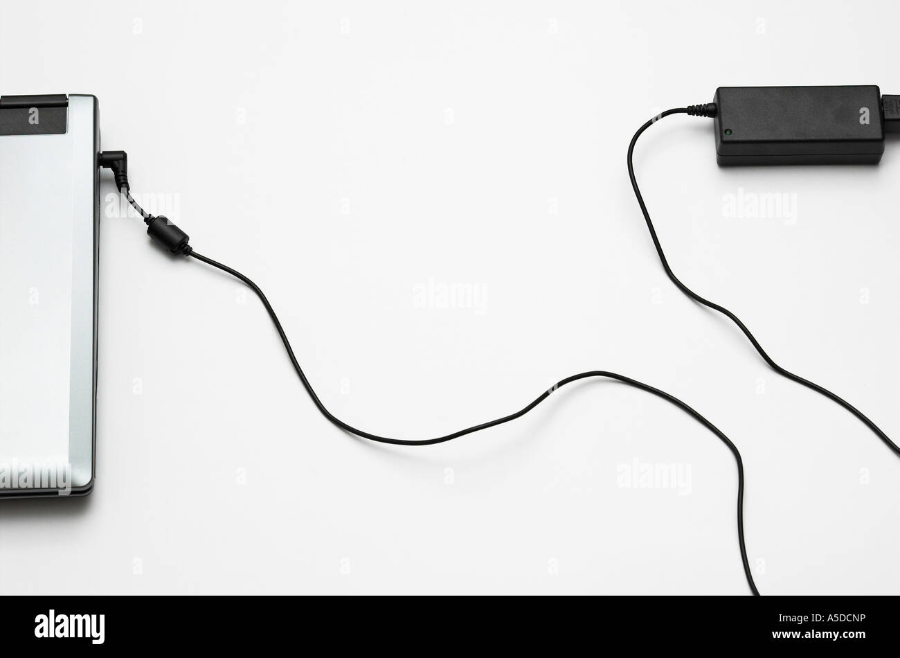 Laptop computer plugged into battery charger Stock Photo - Alamy