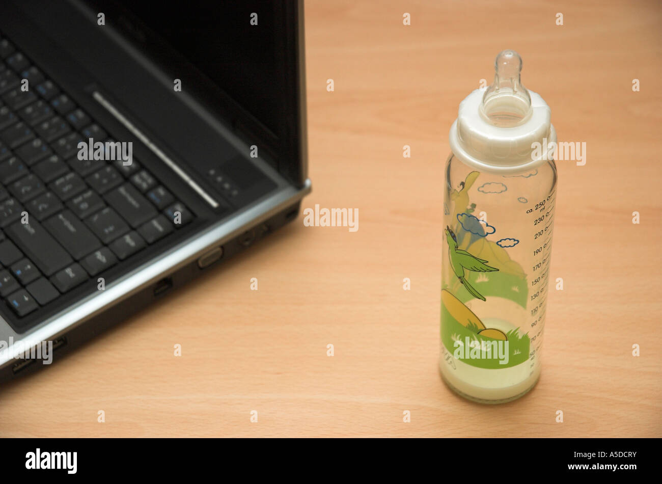 Baby bottle next to laptop on table Stock Photo - Alamy