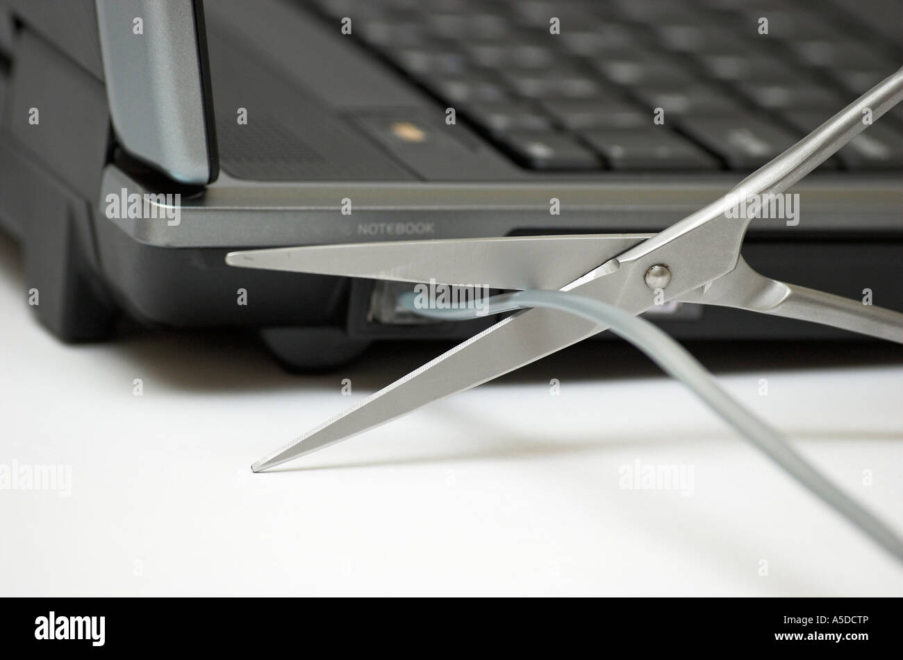 Scissors cutting telephone cable on laptop computer Stock Photo - Alamy