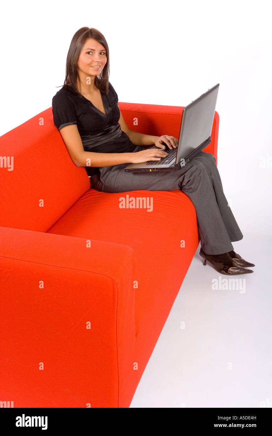 Woman sitting on a red couch with laptop Stock Photo - Alamy