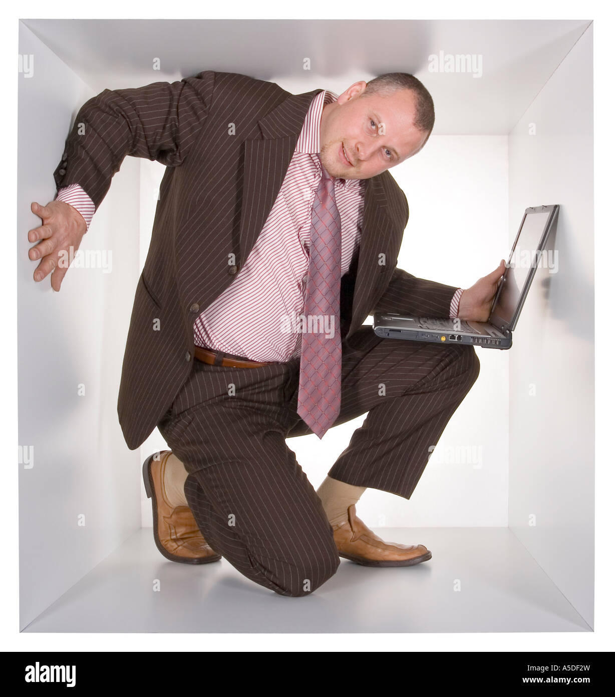 businessman with laptop in the cramped white cube Stock Photo - Alamy