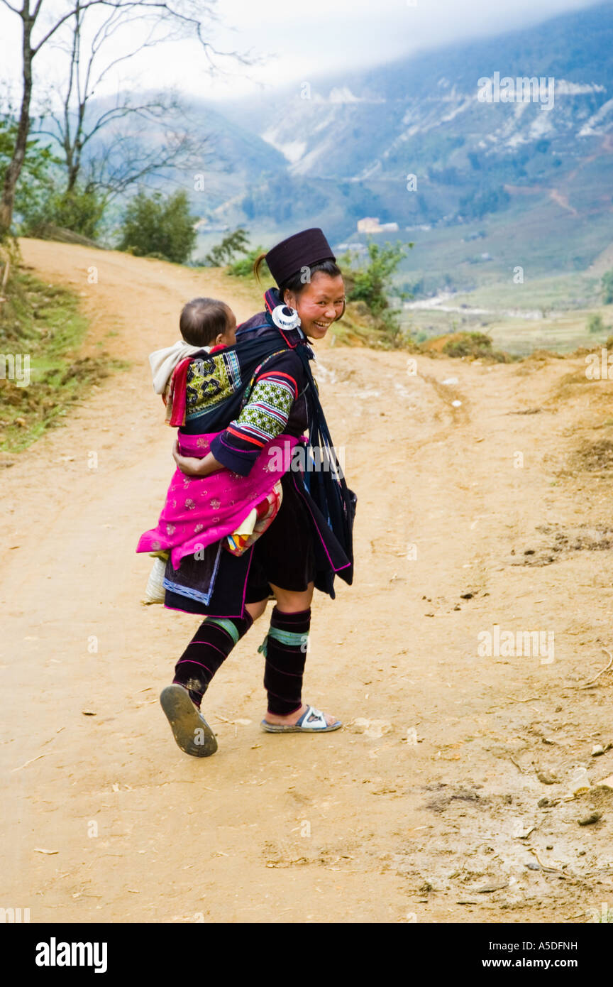 A Black Hmong tribeswoman carries her baby in the hills of Sapa Vietnam ...