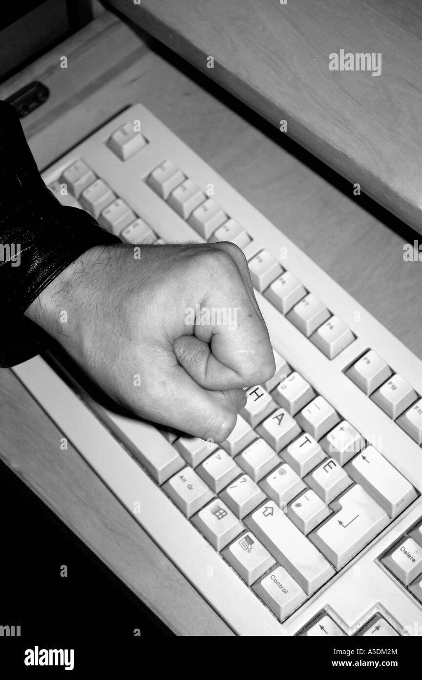 Clenched fist over computer keyboard with the keys spelling the word ...