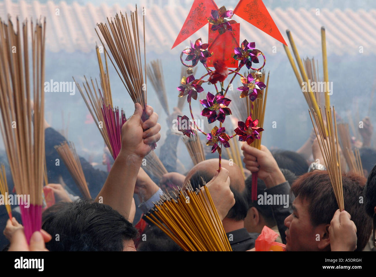 People hold burning joss sticks and lucky pinwheel during Lunar New ...